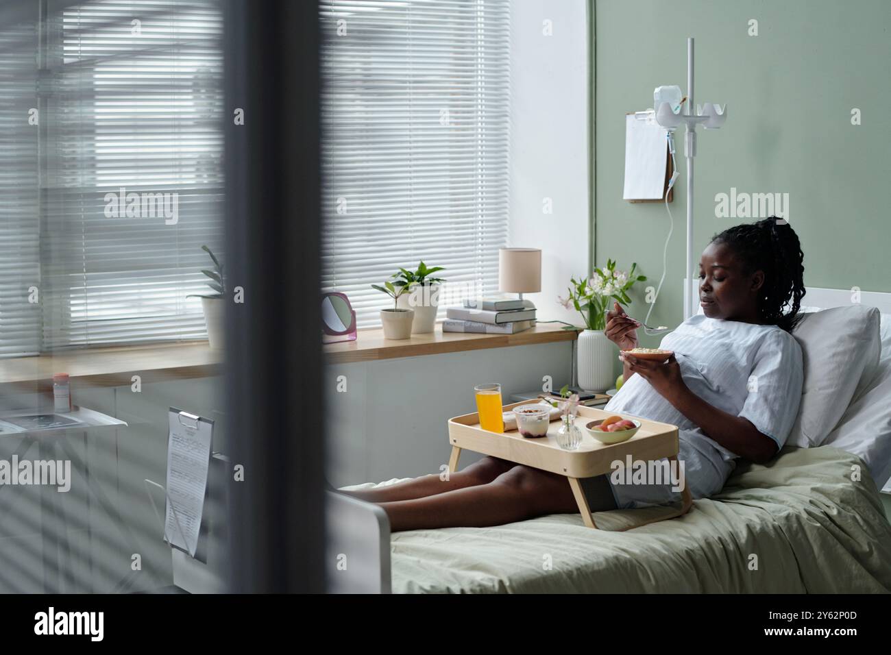 Patient in hospital room with tray of food on bed, enjoying breakfast ...