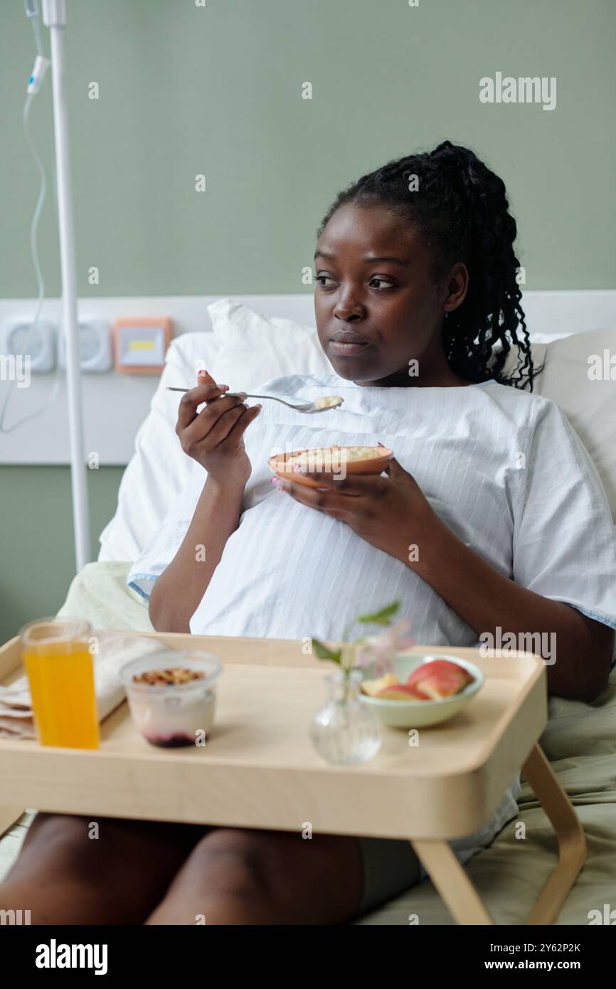Woman sitting in hospital bed enjoying breakfast while recovering from ...