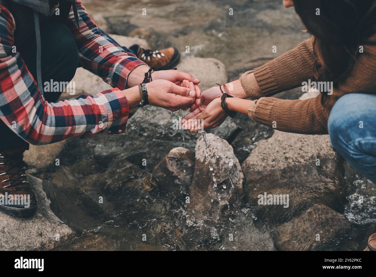 Real refreshment. Close up of young couple washing hands in the river ...
