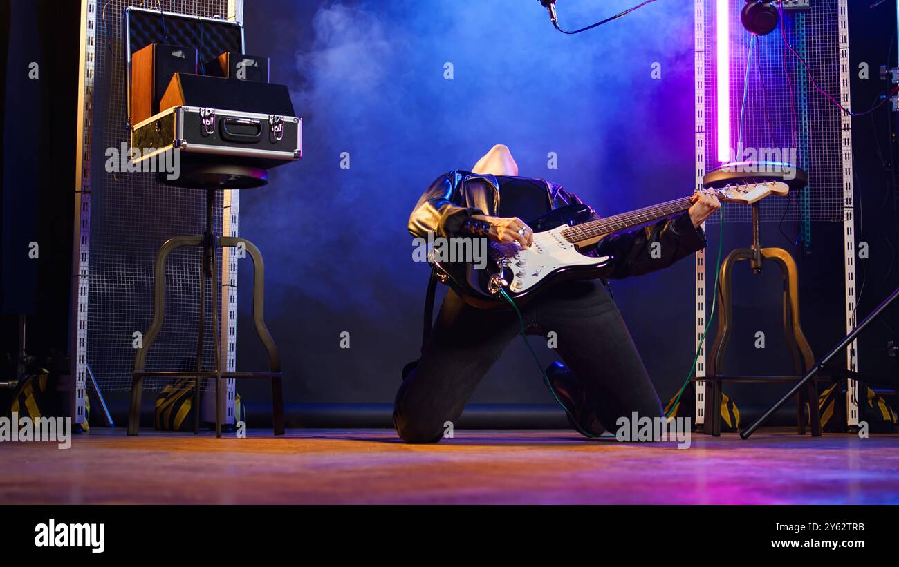 Confident female rocker performing live with a bass guitar on stage ...
