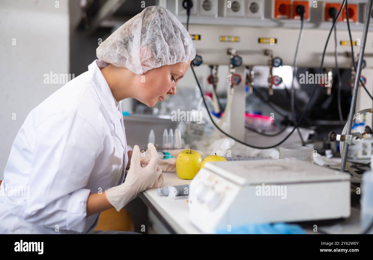Woman lab technician analyzing apple in laboratory Stock Photo - Alamy
