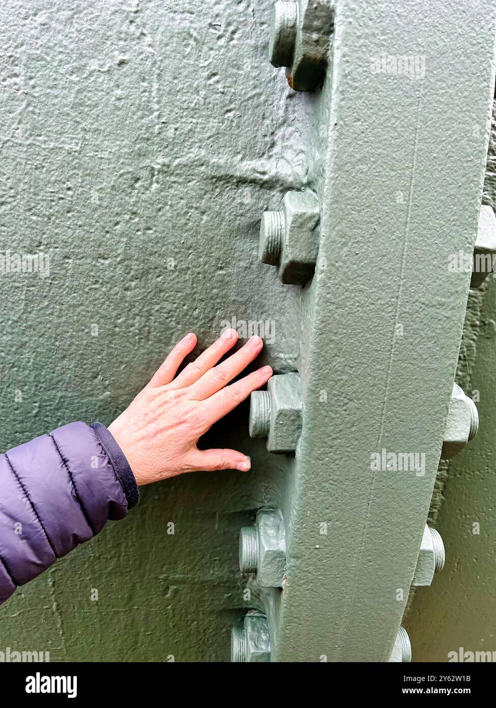 A woman's hand shows large bolts and nuts on a technical installation ...