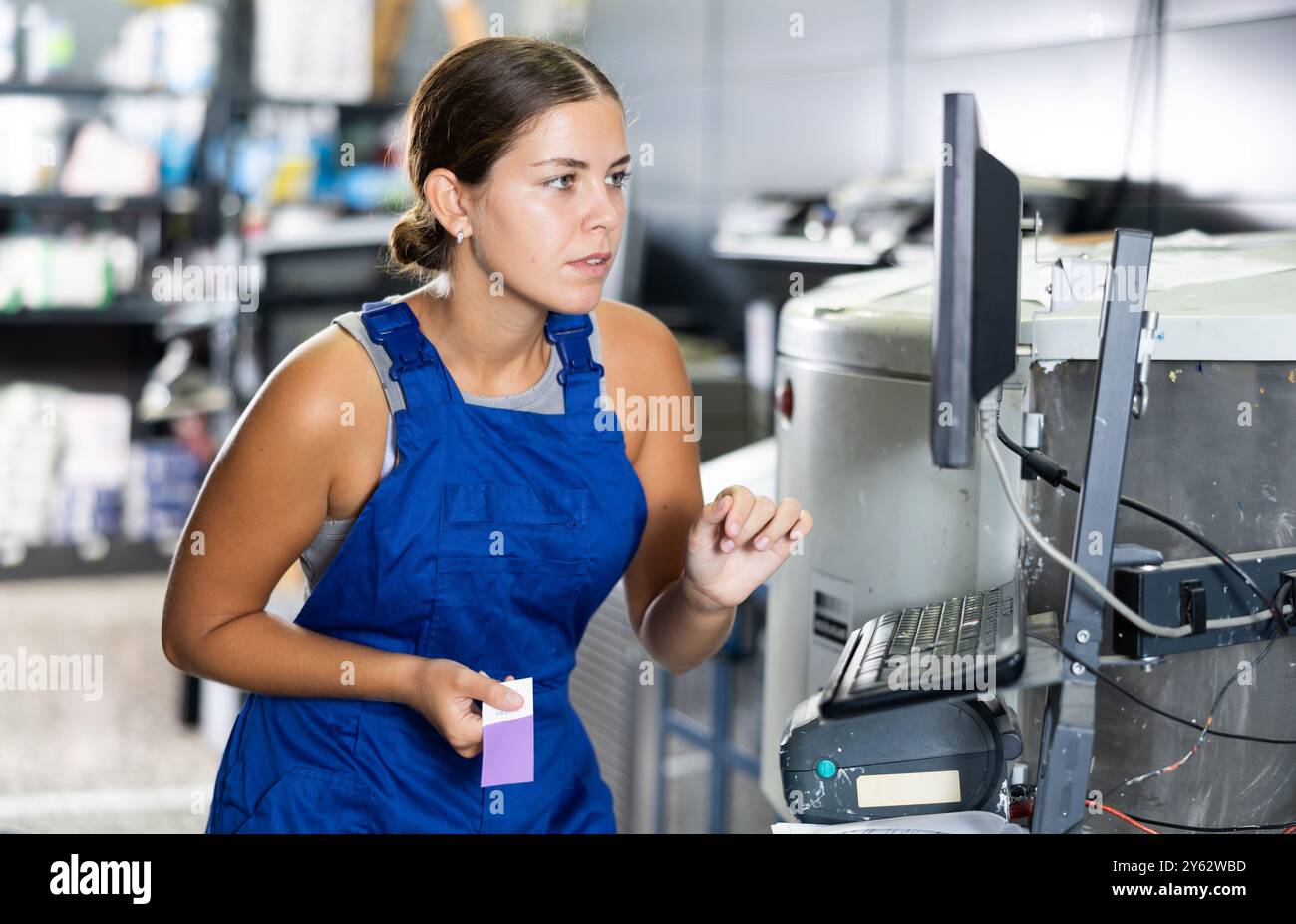 Woman in uniform operating computerised machne to mix paint Stock Photo ...