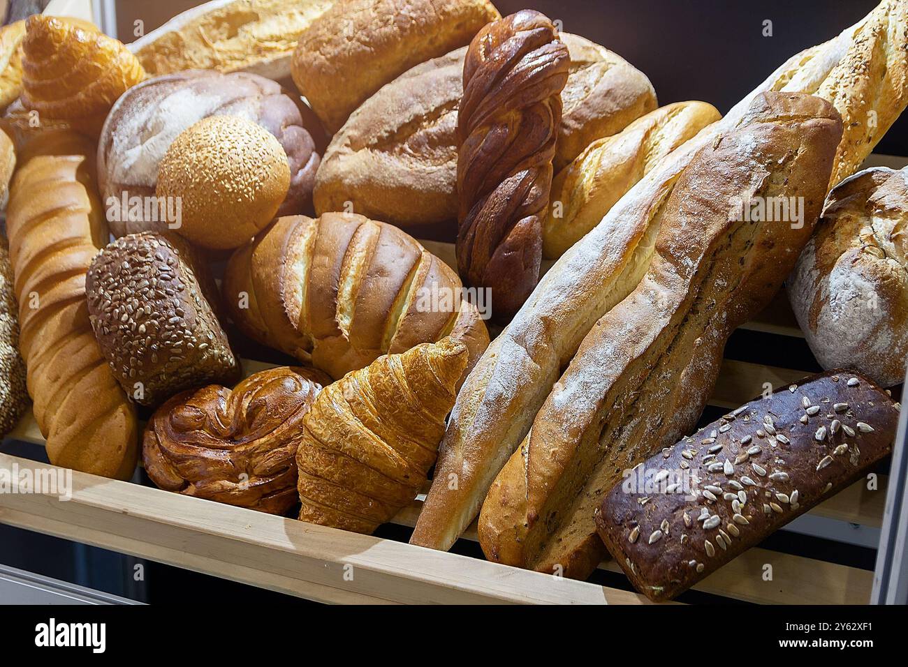 A bakery counter with an array of bread loaves, rolls, and baguettes ...