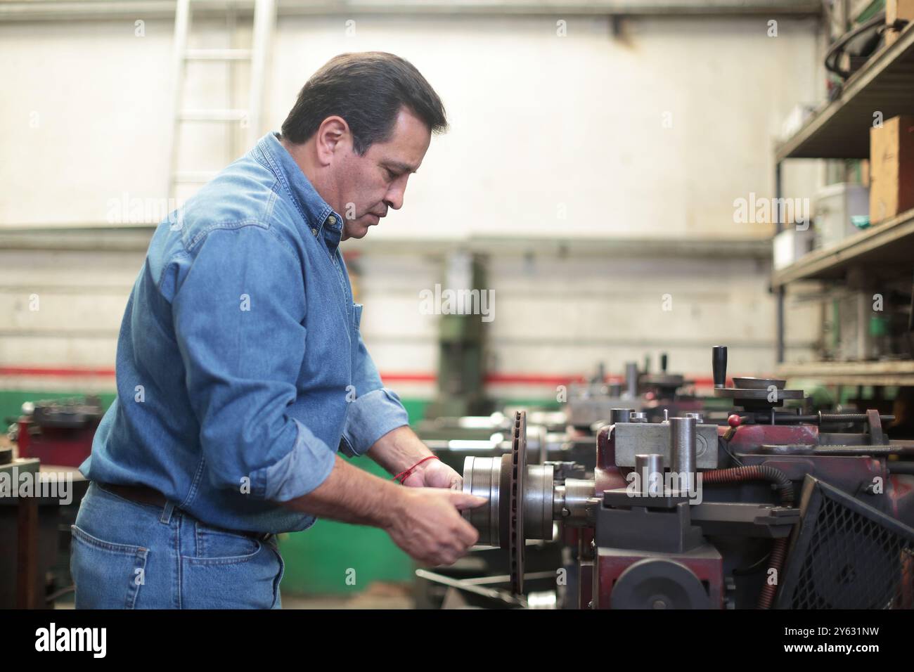 Mechanic adjusts lathe to grind brake disc Stock Photo - Alamy
