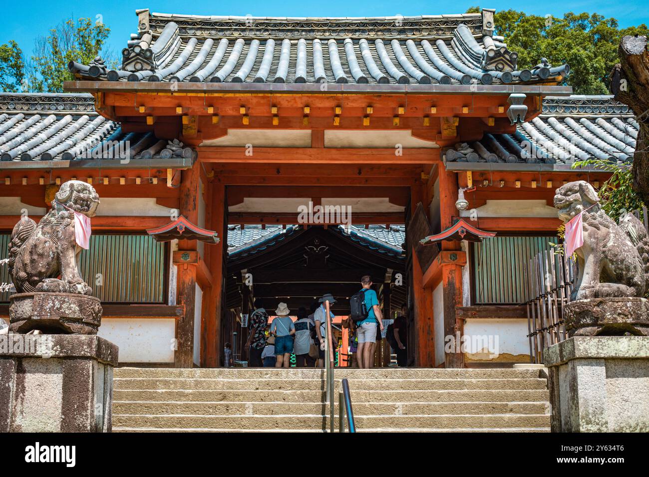 Tourists entering a traditional Japanese temple gate with stone ...