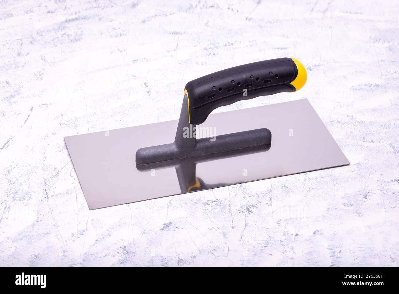 Trowel with black-yellow handle to the smoothing of plaster on white ...