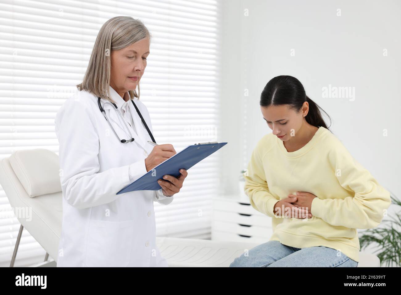 Senior doctor consulting patient with stomach pain in hospital Stock ...