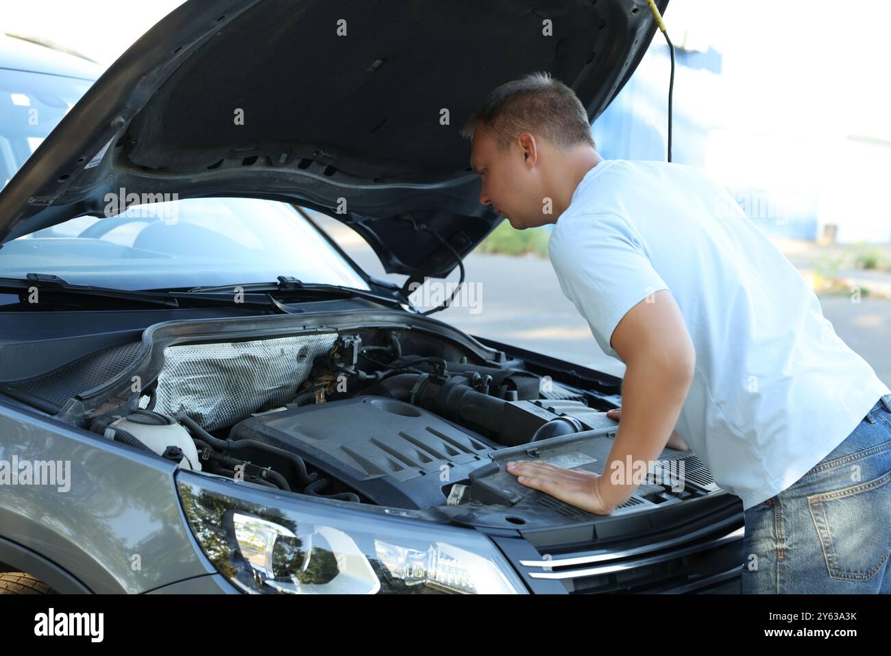 Stressed man looking under hood of broken car outdoors Stock Photo - Alamy