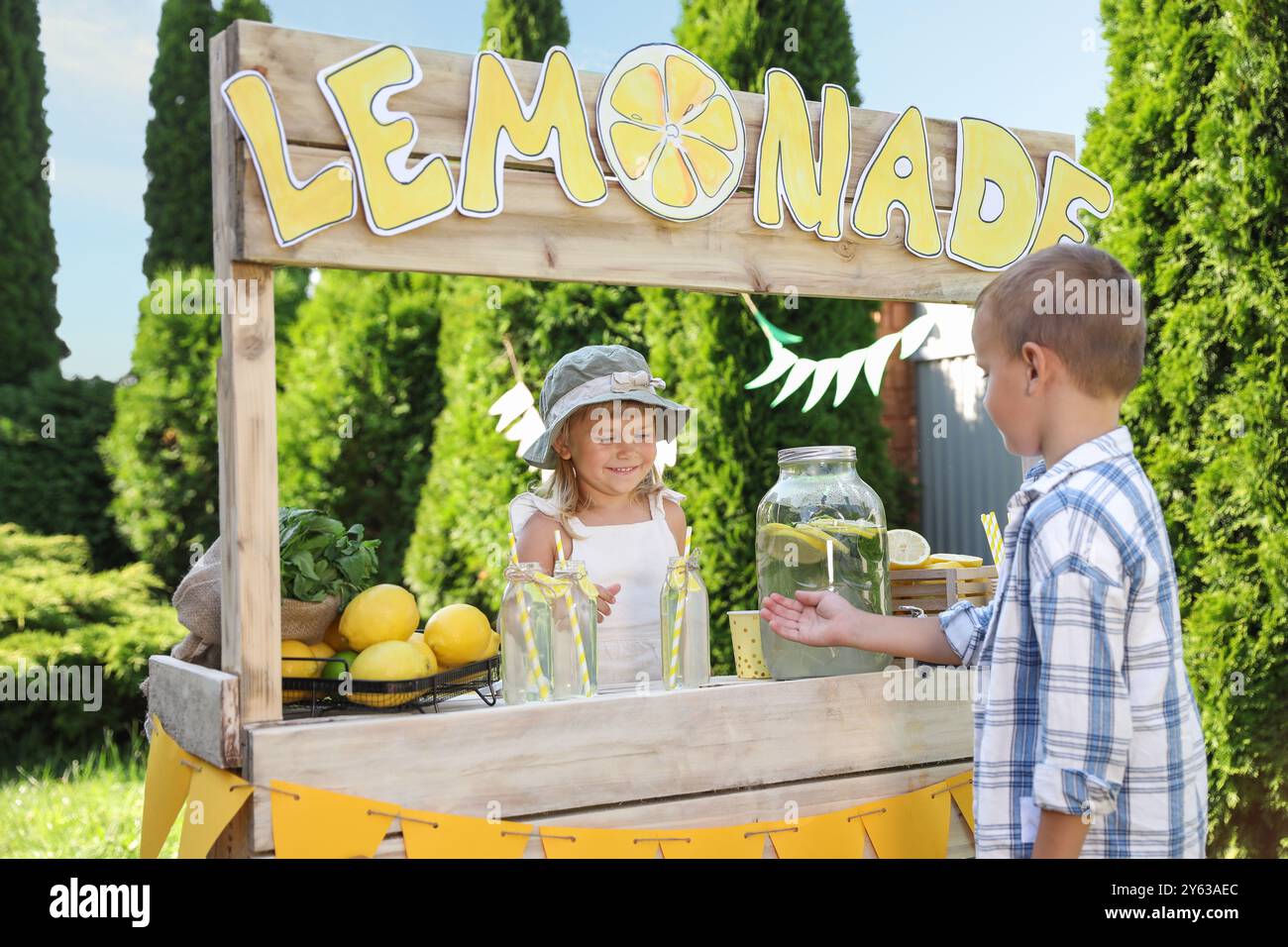 Cute little girl selling natural lemonade to boy in park Stock Photo ...