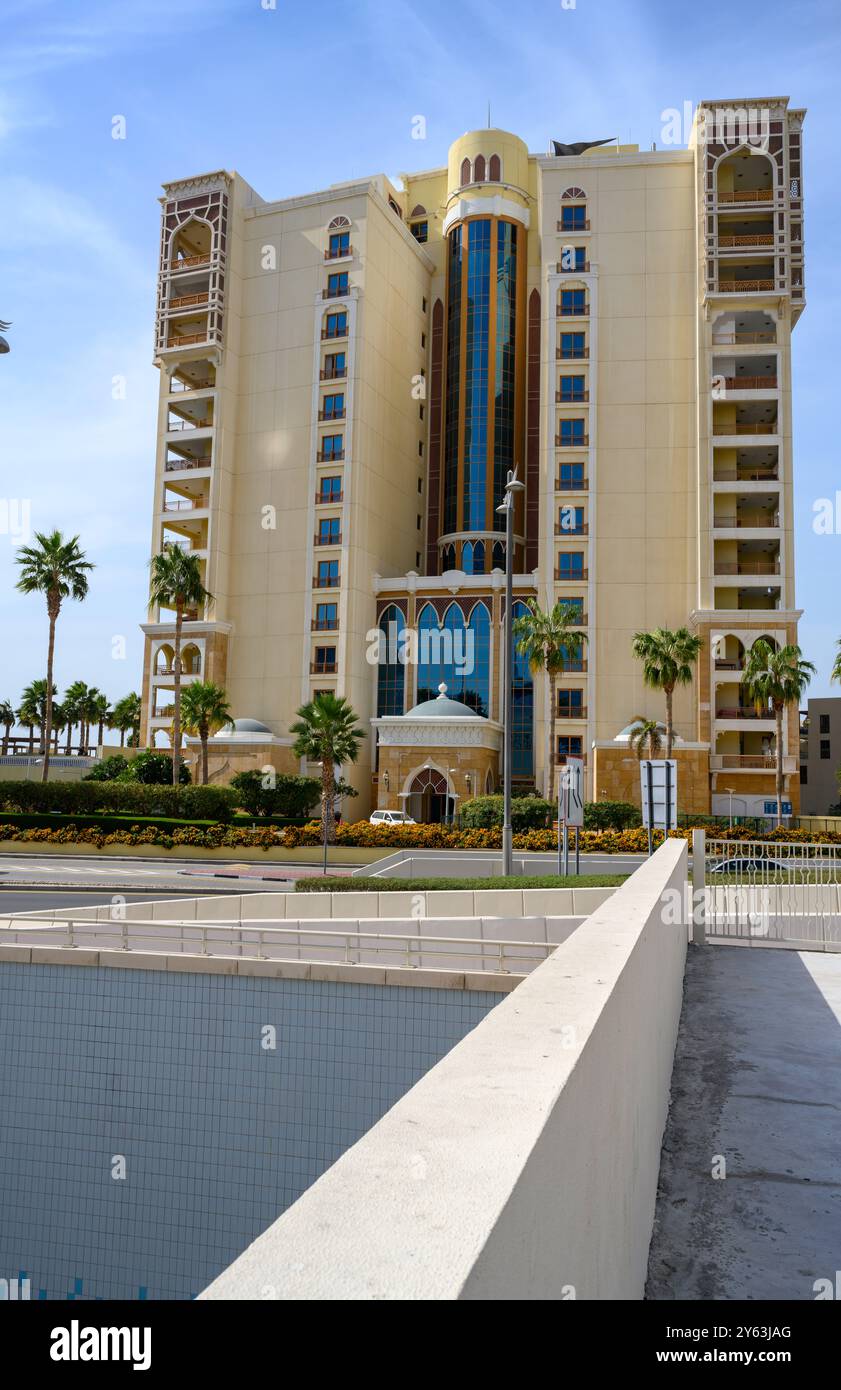 A street with palm trees and a tall apartment building in Dubai, United ...
