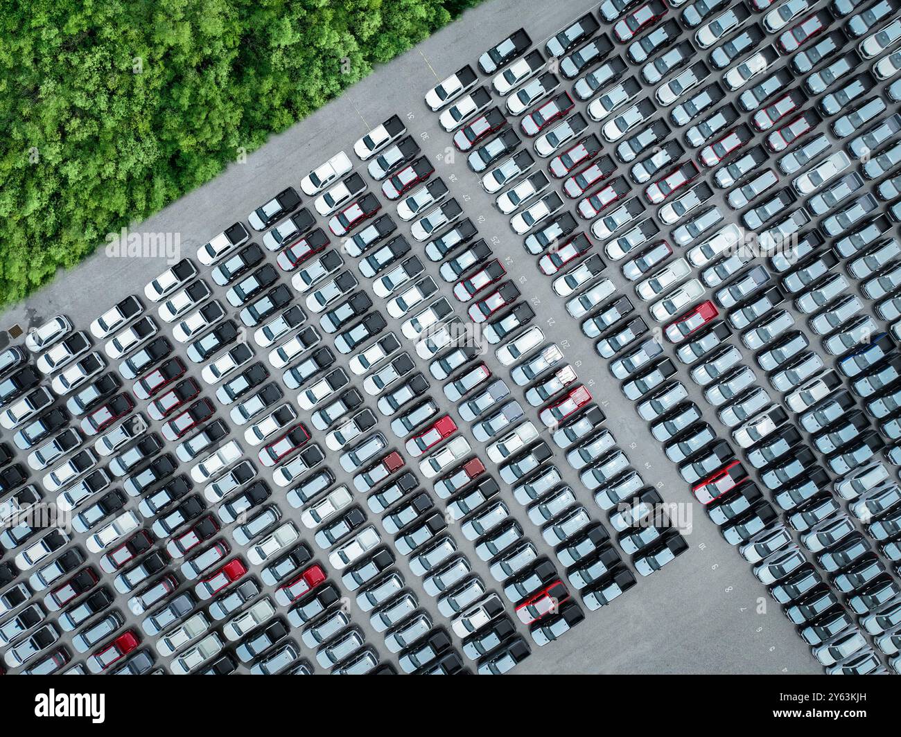 Aerial view of a factory parking lot filled with new cars adjacent to ...