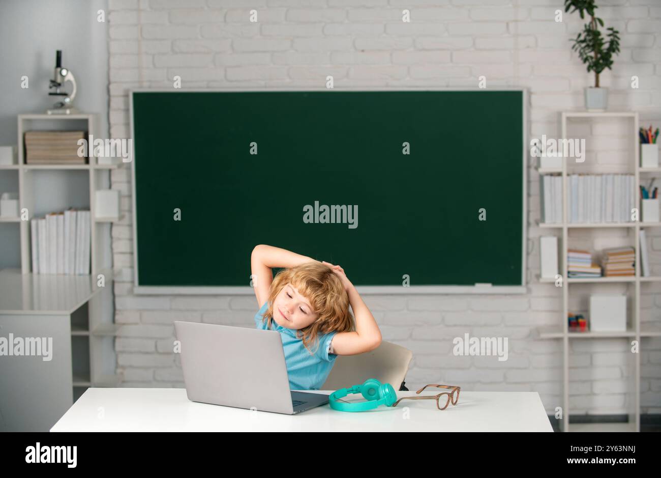 Cute little school kid boy study in a classroom. Portrait of pupil rest ...