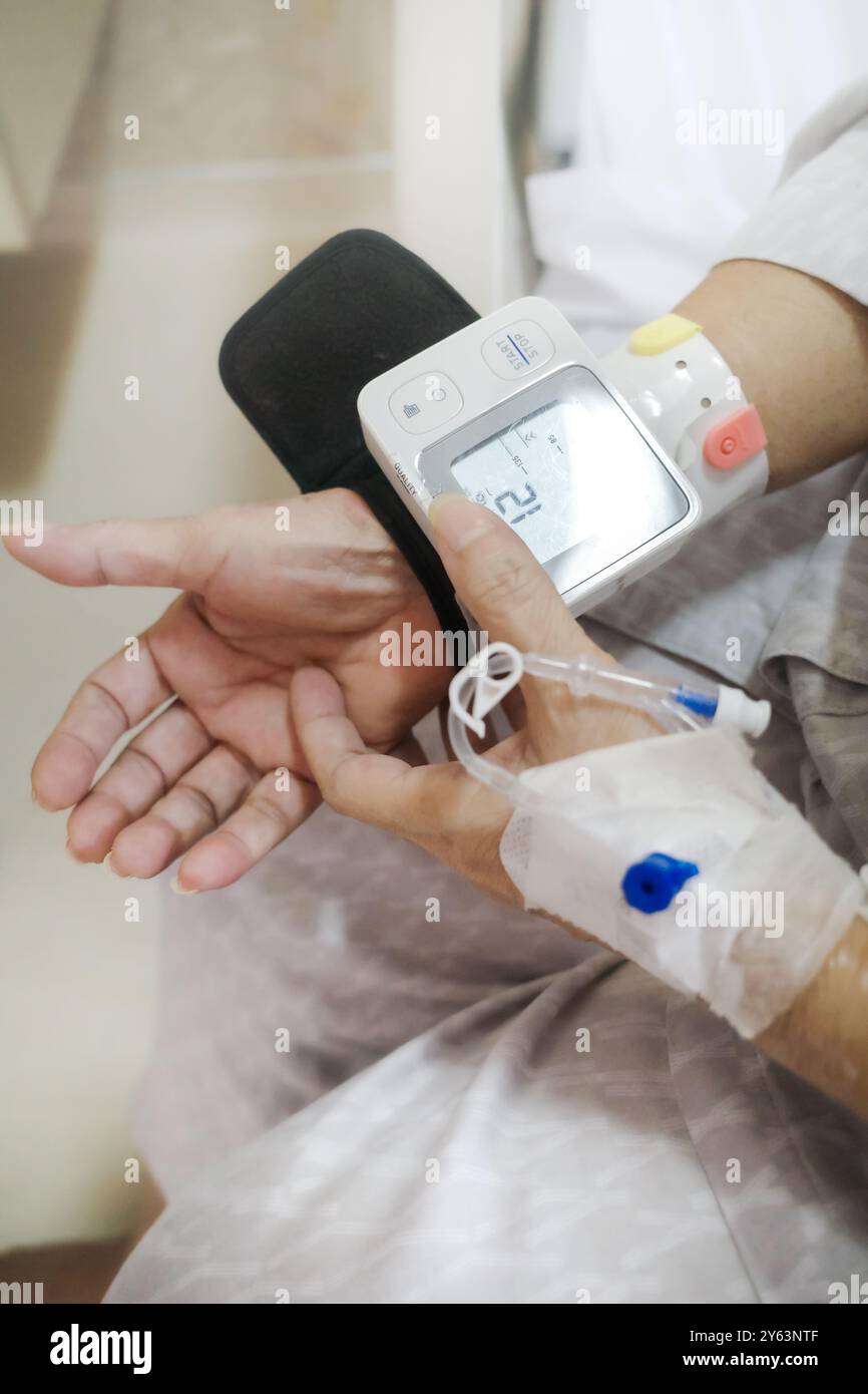 Mature adult female patient using digital blood pressure and heart rate ...