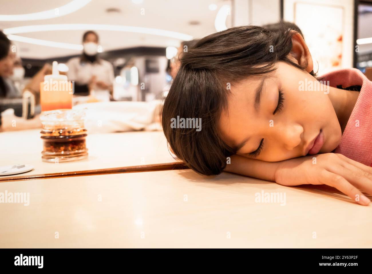 An Asian boy falling asleep on the table while waiting for dinner at a ...
