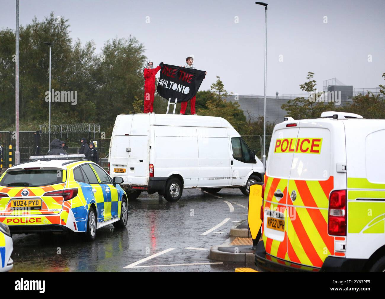Police vehicles surround the van with the protesters waving a banner on ...