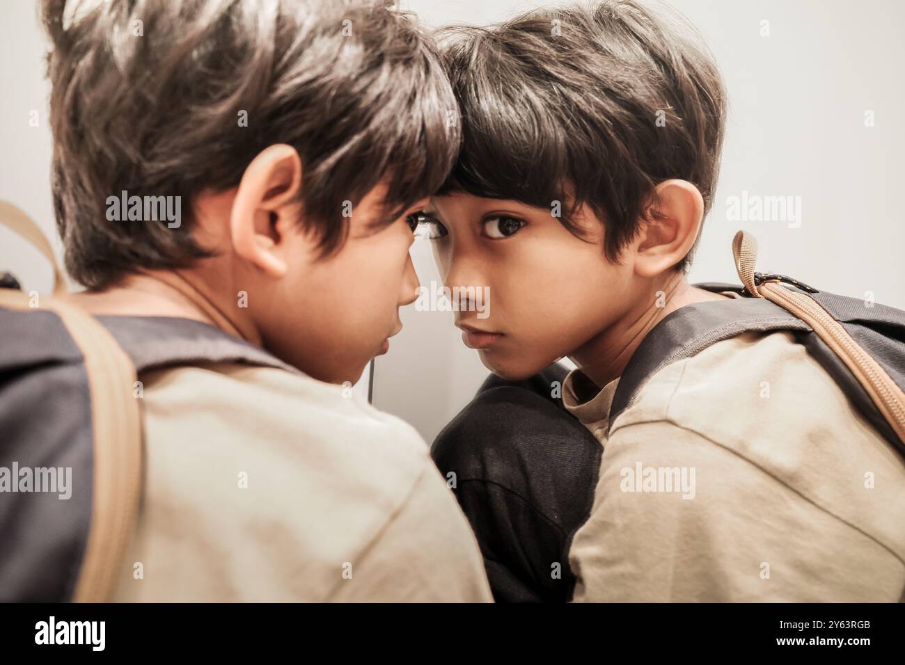 A Southeast Asian Boy Sitting in Front of a Mirror with Bored ...