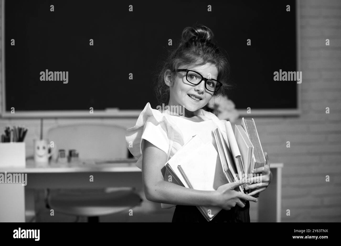 Portrait of cute, lovely, girl in school uniform holding books in ...
