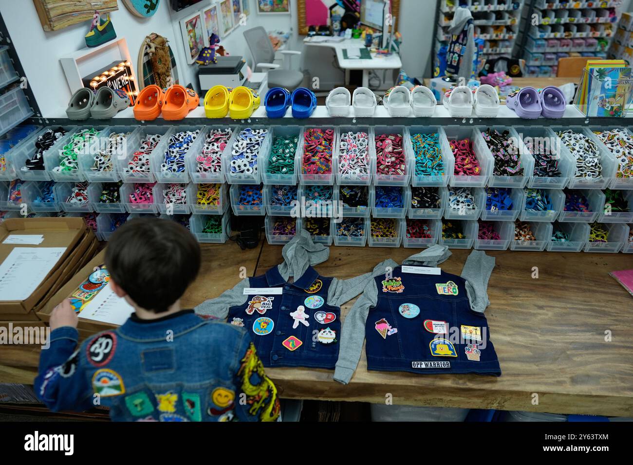 Oliver Burkhardt, 13, shows how staff lays out patches on denim jackets ...