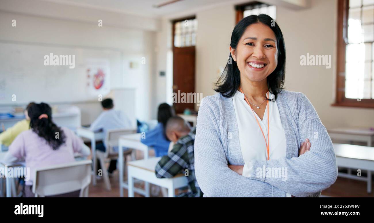 Teacher, portrait and arms crossed in classroom with students for ...