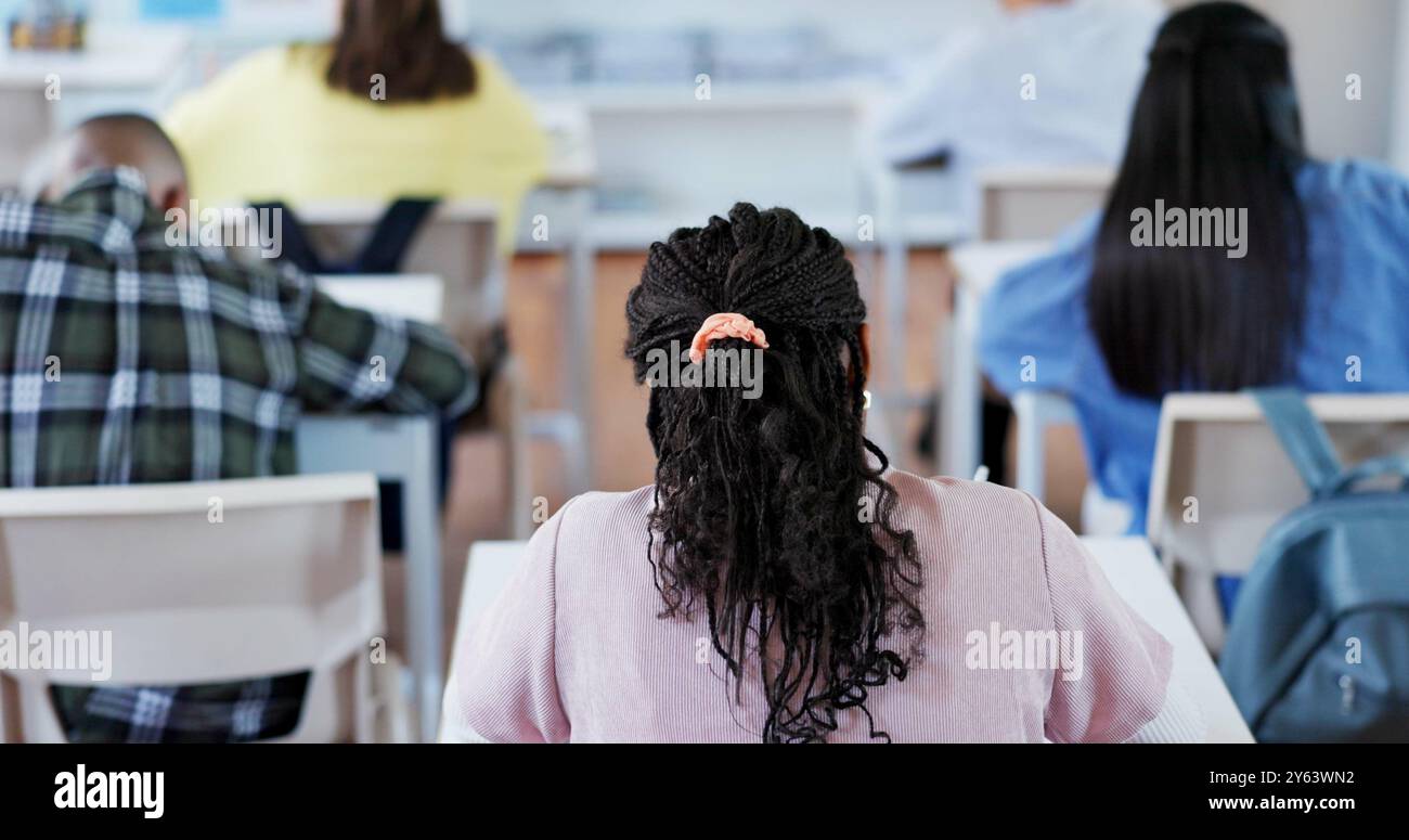 Education, study and writing with back of students in classroom for ...