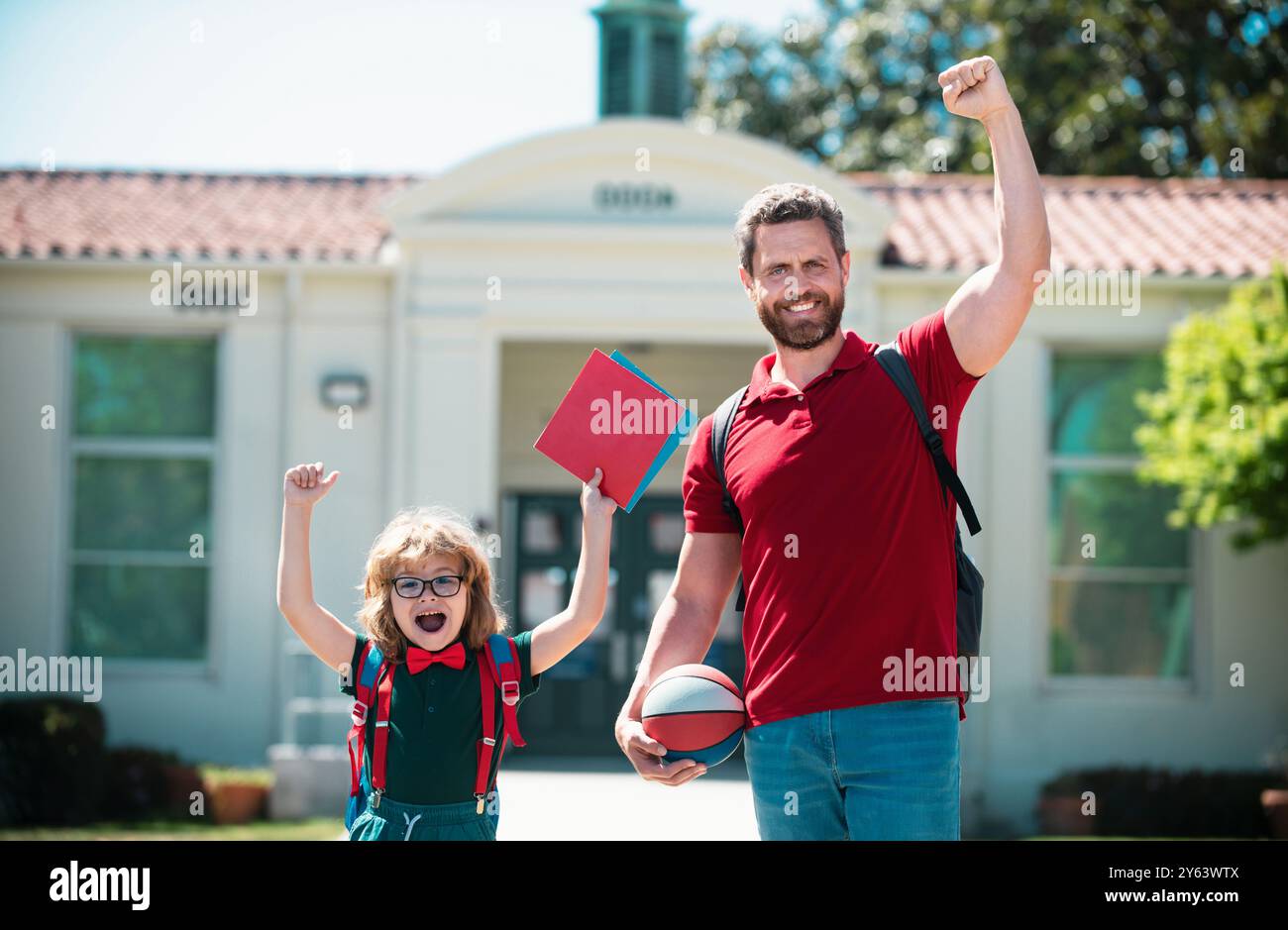 Teachers day. Portrait of amazed dad and son in front of school in good ...
