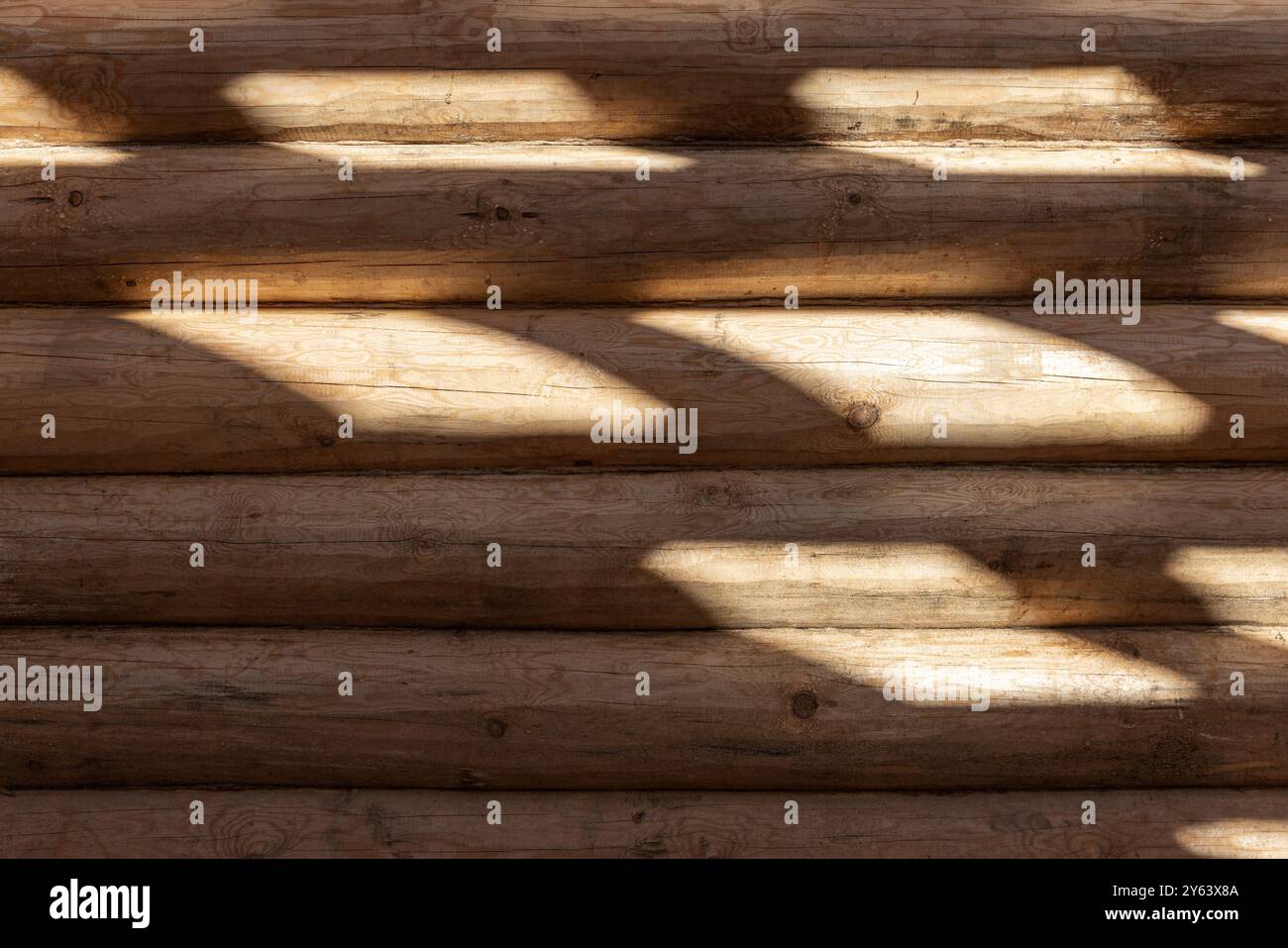 New wooden wall made of uncolored natural pine tree logs with shadow ...