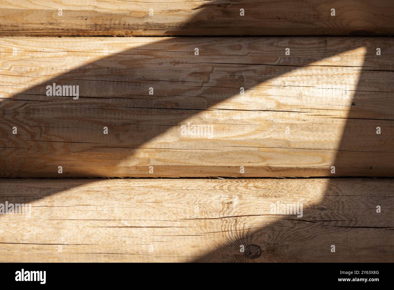 Wooden wall made of uncolored natural hewn pine logs with shadow ...