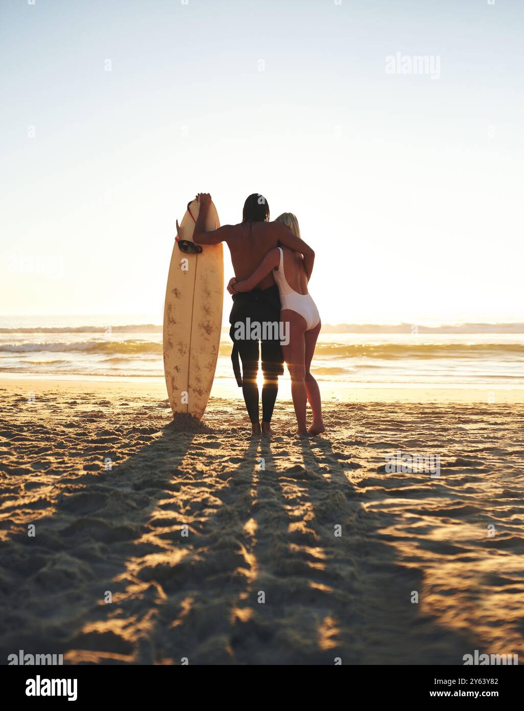 Seaside, couple and hug with surfboard for love in bonding, break and ...