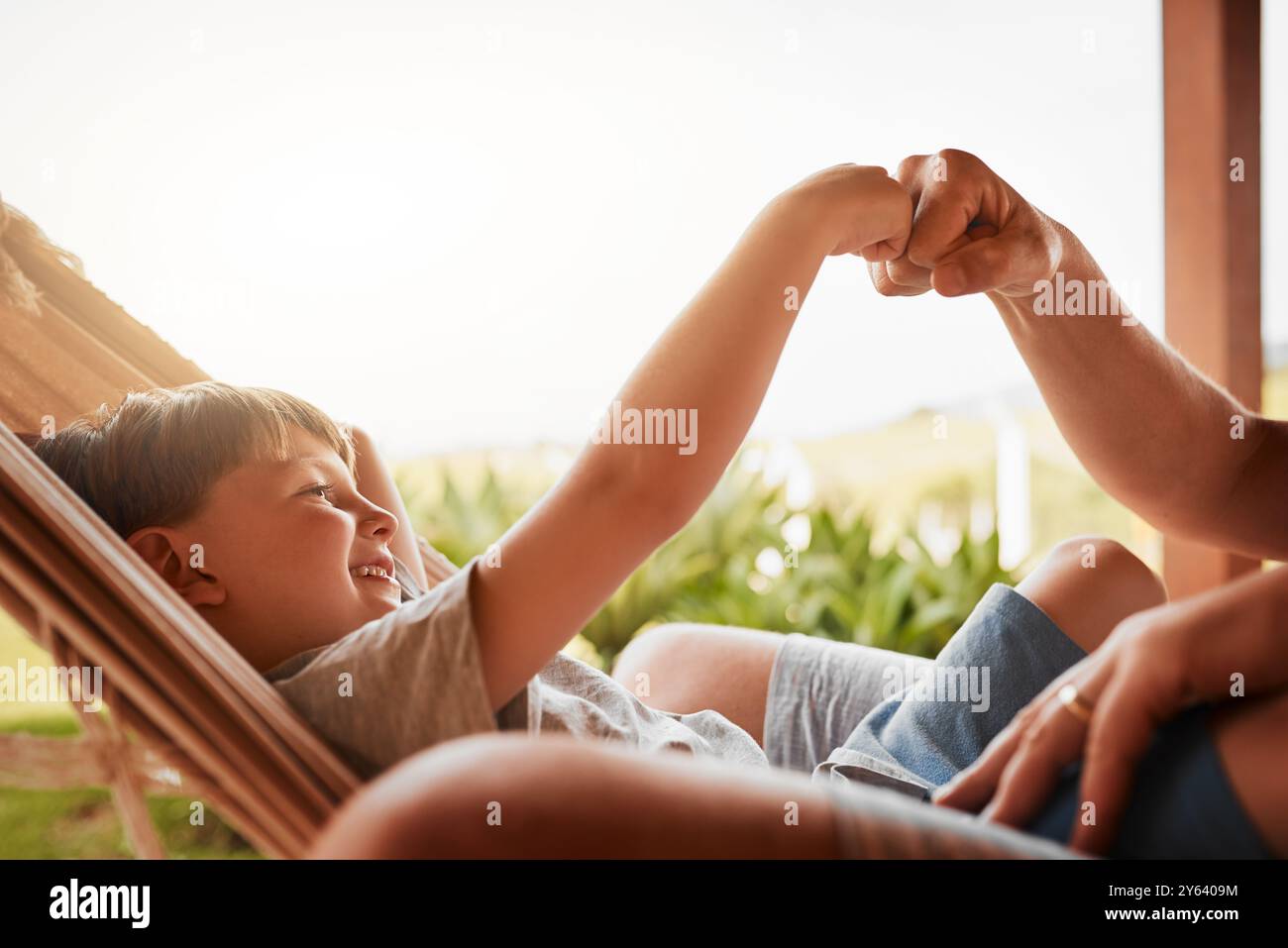 Smile, child and fist bump with parent outdoor for family support, love and care on hammock. Boy ...