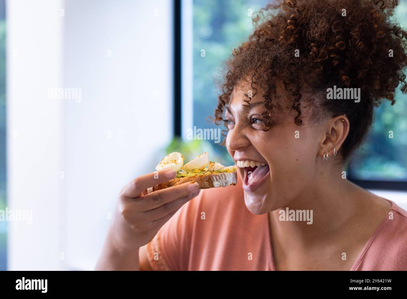 Eating healthy toast, woman enjoying nutritious snack in bright room ...