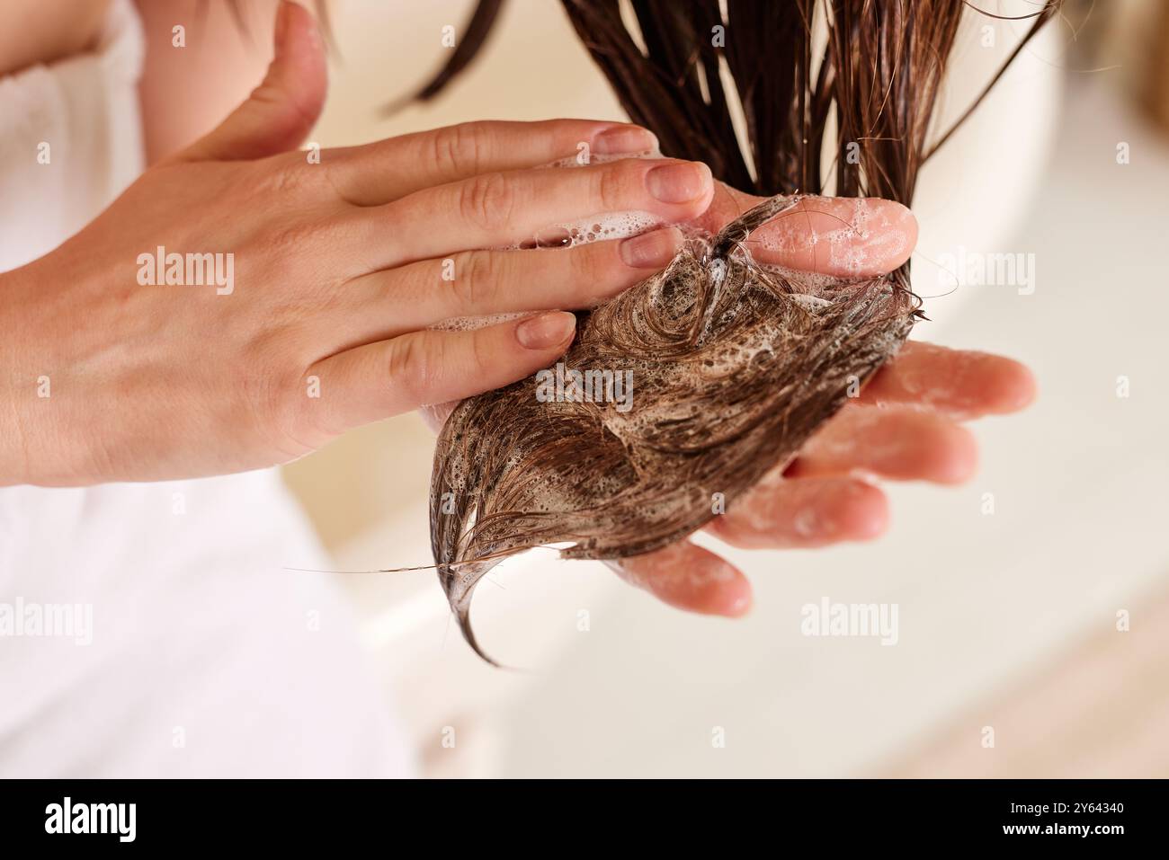 Close-up of a woman washing her hair and applying shampoo with her ...