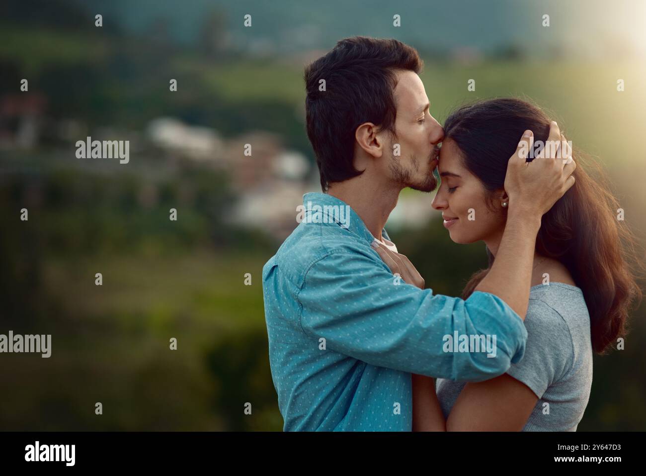 Love, forehead and kiss with couple in nature for support, bonding and ...