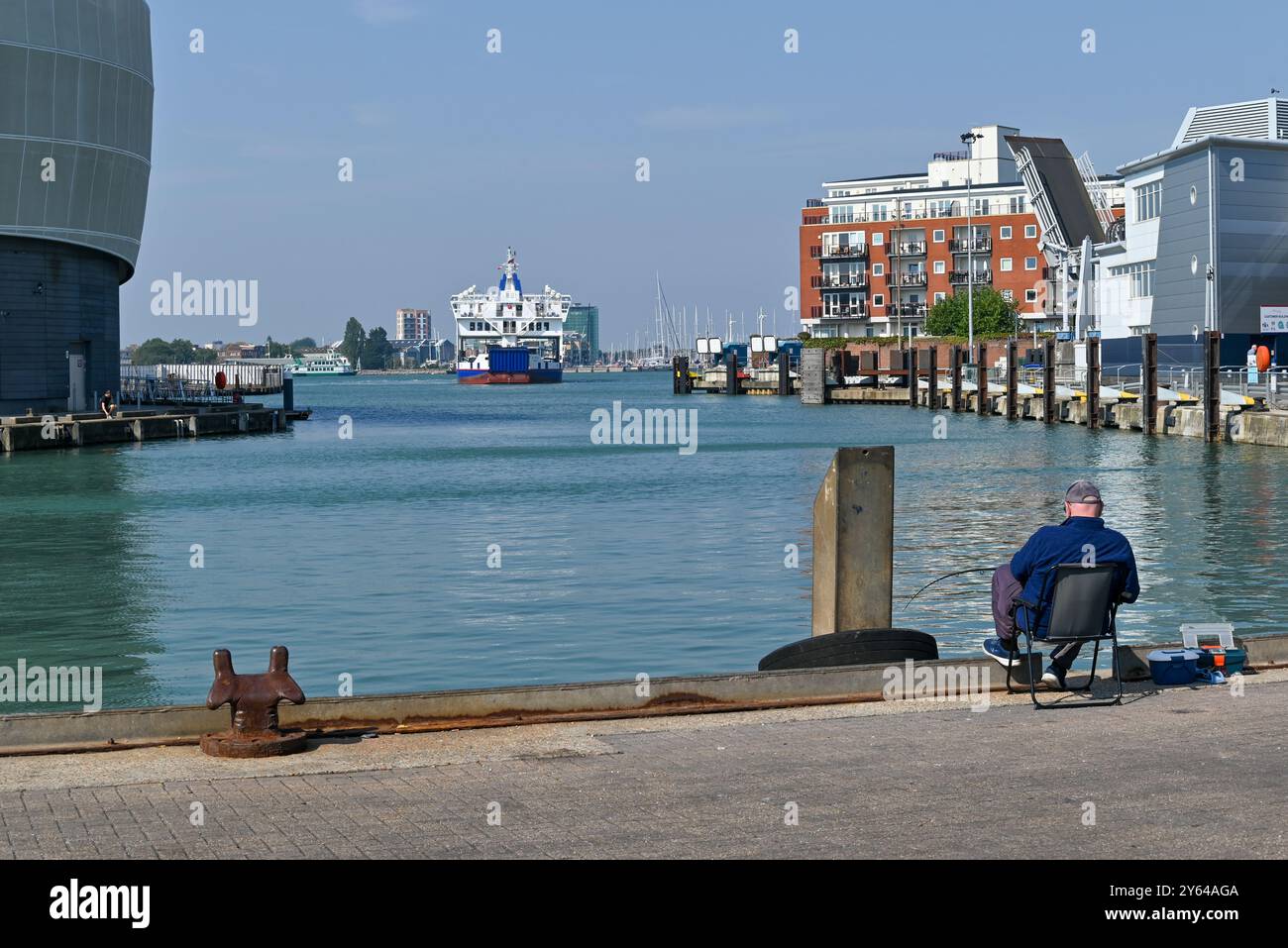 Man relaxing and fishing at Camber dock with an Isle of Wight car ferry ...