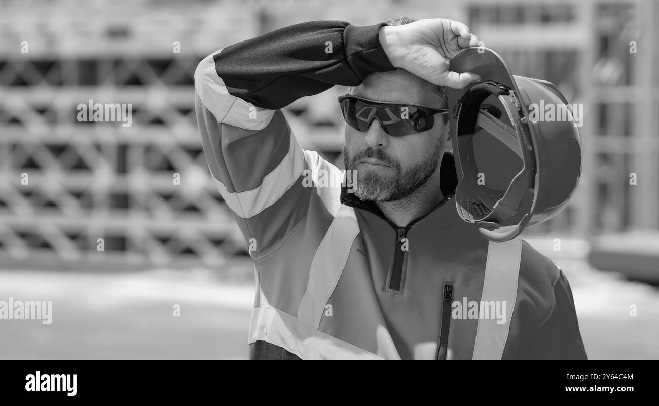 Tired, overworked worker in building uniform on buildings construction ...