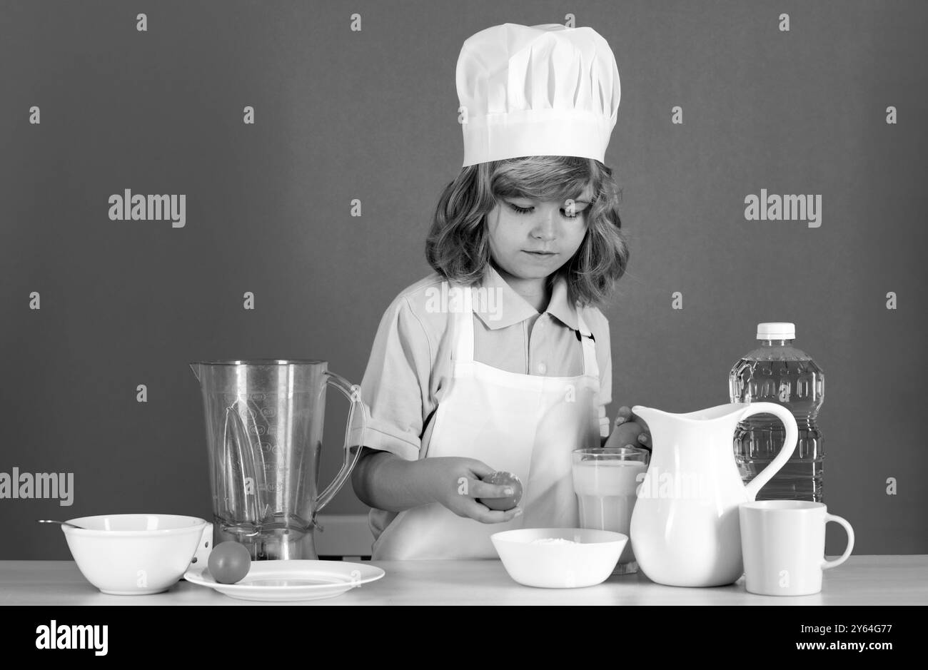 Child chef cook prepares food in isolated blue studio background. Kids ...