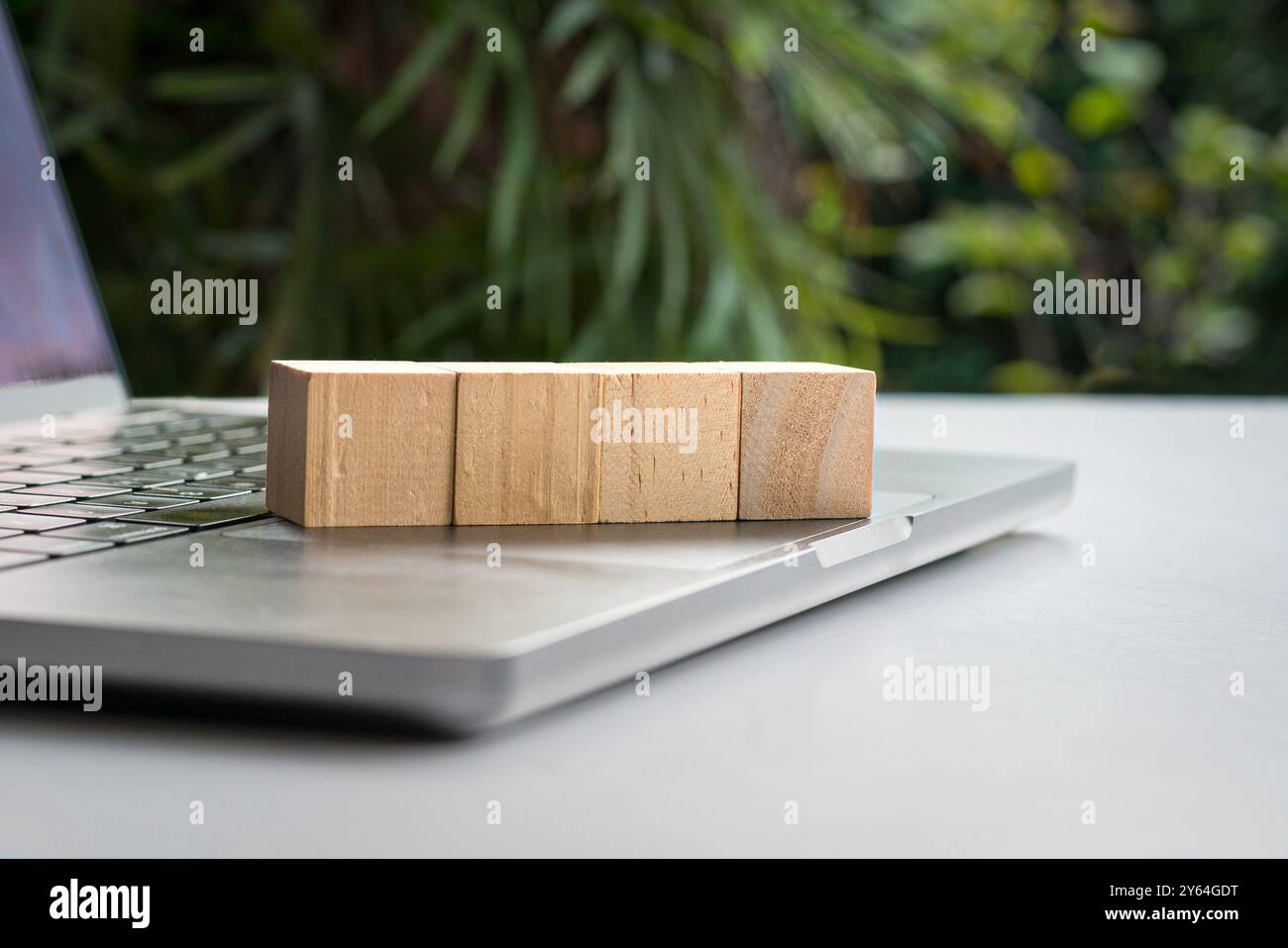 Four blank wood square toy blocks on top of computer laptop, with palm ...