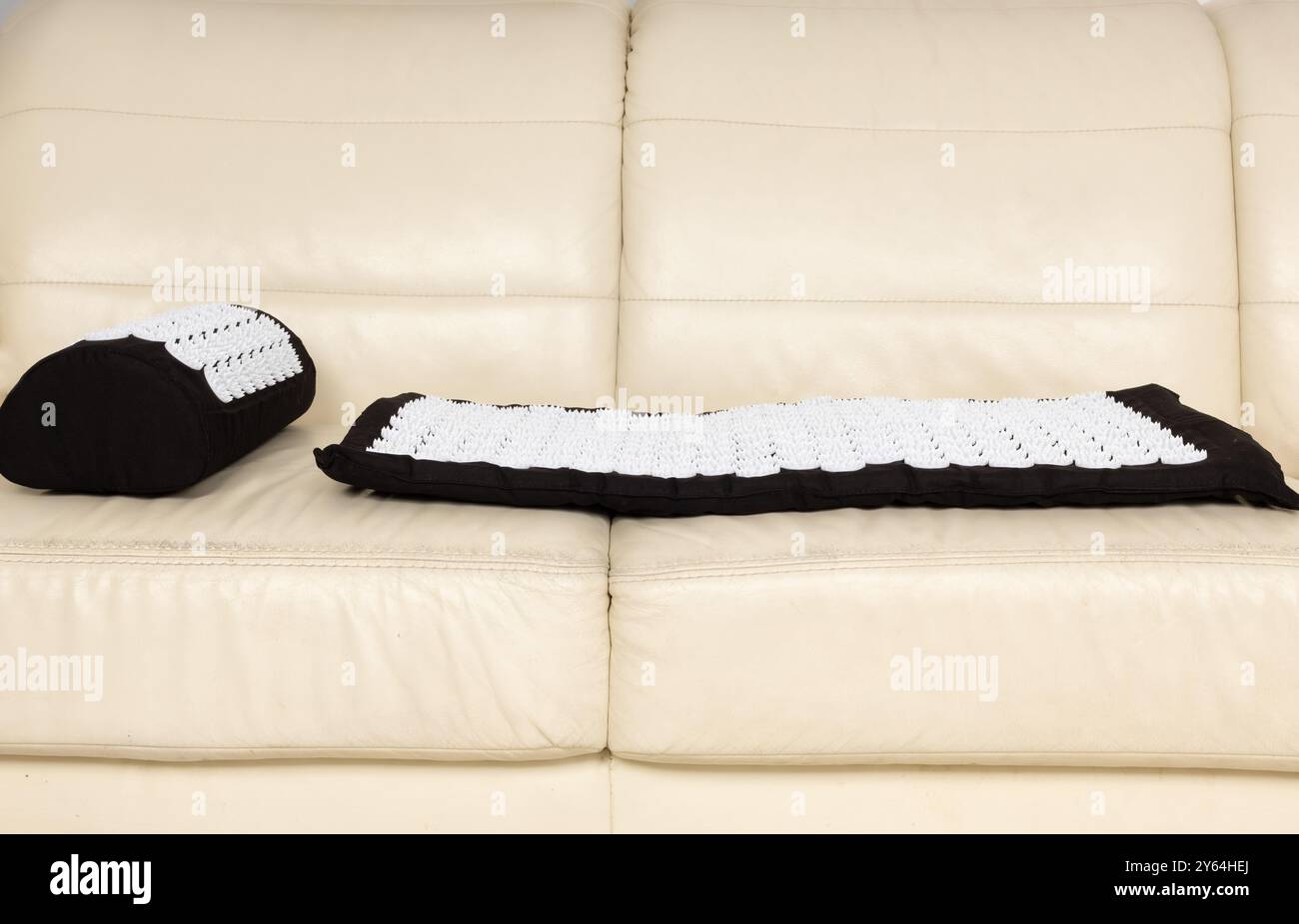 Acupressure mat and pillow on white leather couch Stock Photo - Alamy