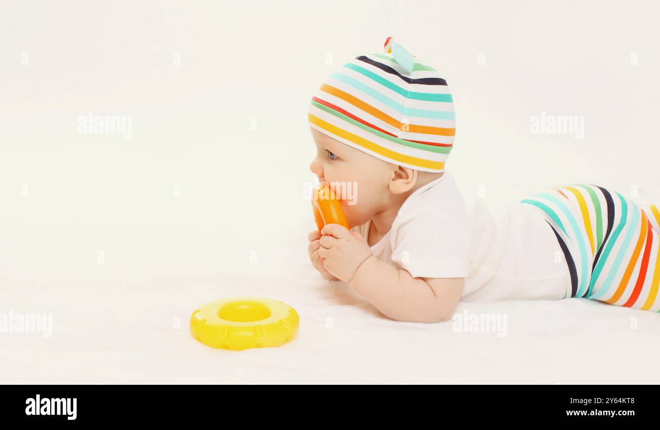 Happy little baby playing with toys while sitting on floor on white ...
