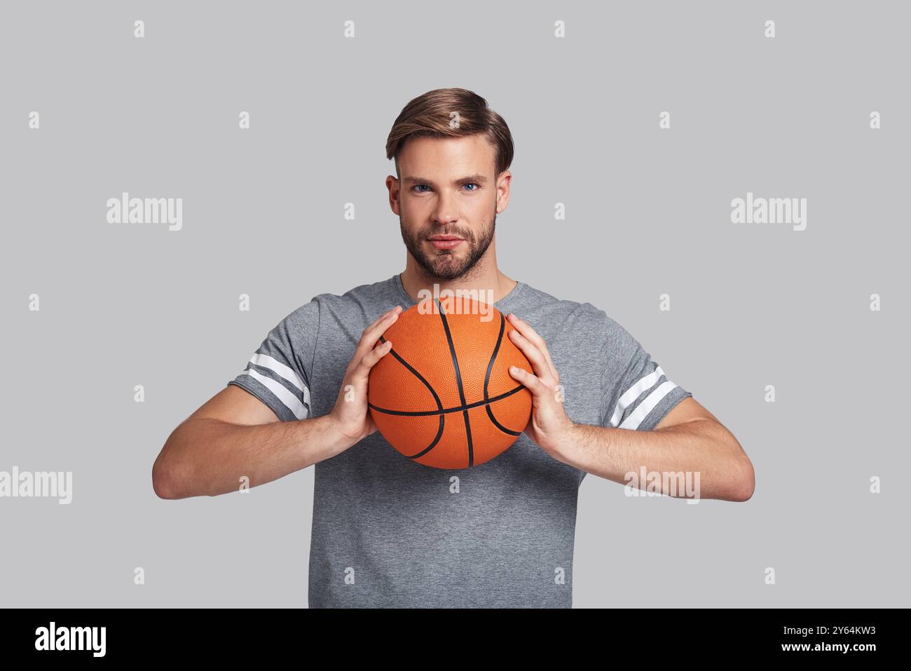 Best sport. Handsome young man carrying a basketball ball and looking ...