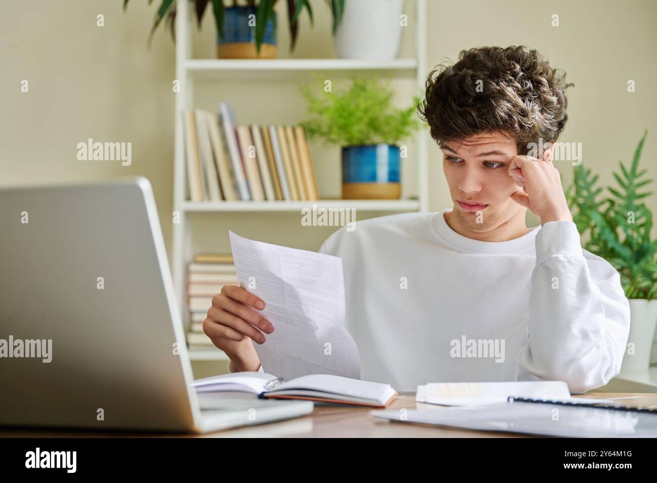 Serious young guy reading letter, paper document Stock Photo - Alamy