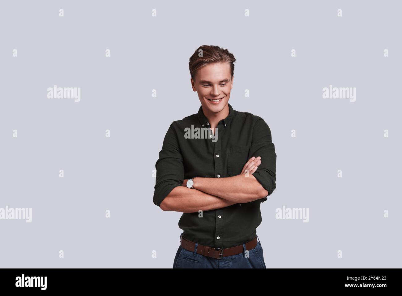 Too good to be real. Good looking young man keeping arms crossed while ...