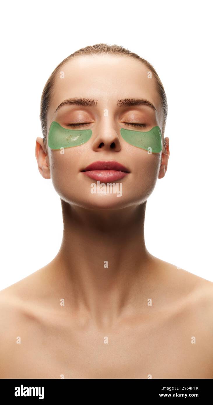 Young woman with clear, spotless skin applying under eye refreshing ...