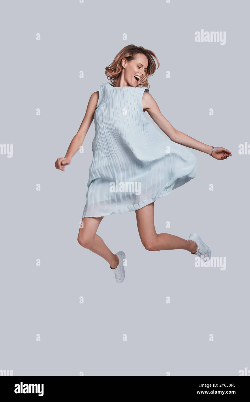Going crazy. Full length of playful young woman smiling while jumping ...