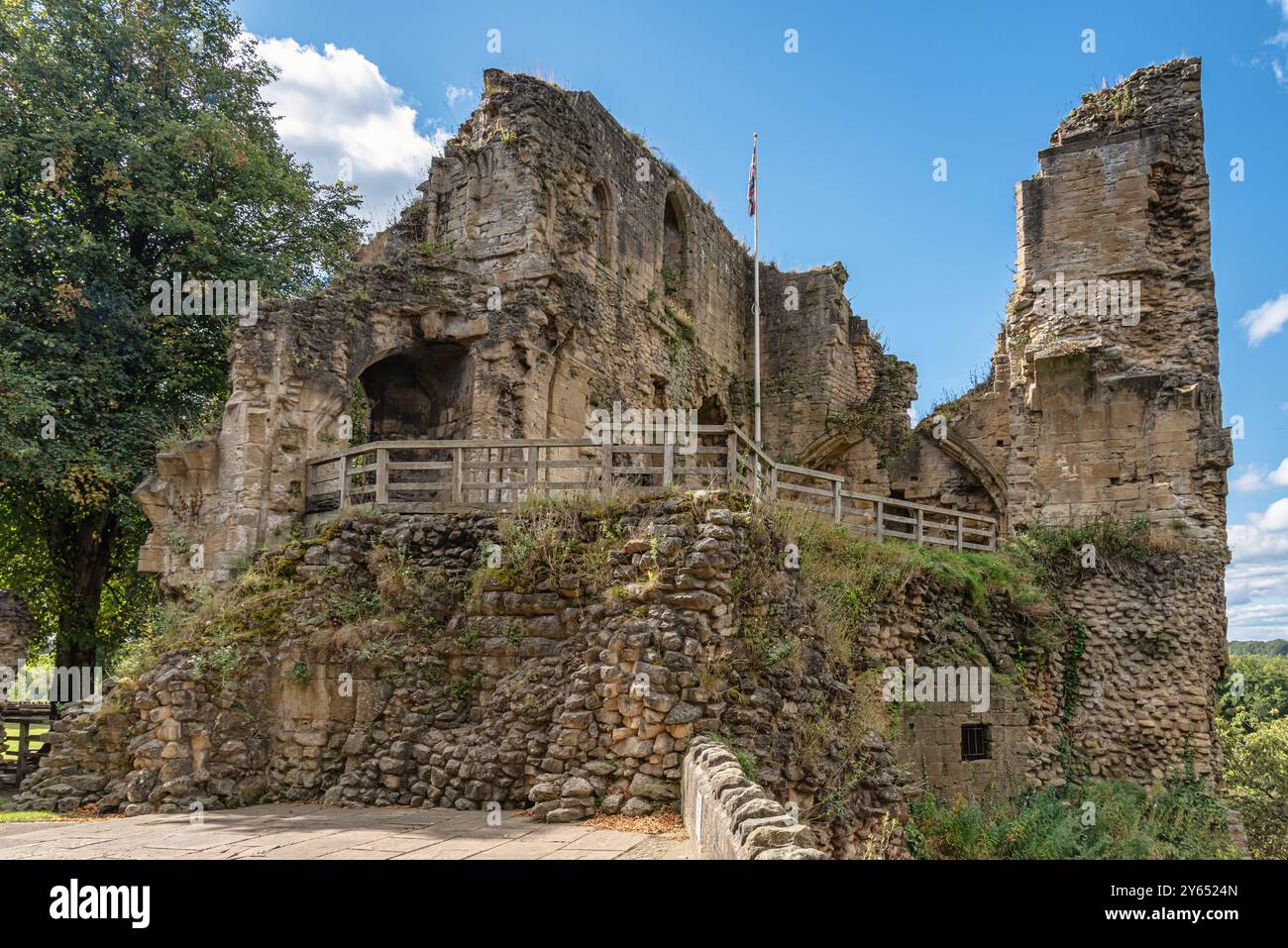 The ruins of a medieval castle set against a sky with cloud. A tree is ...