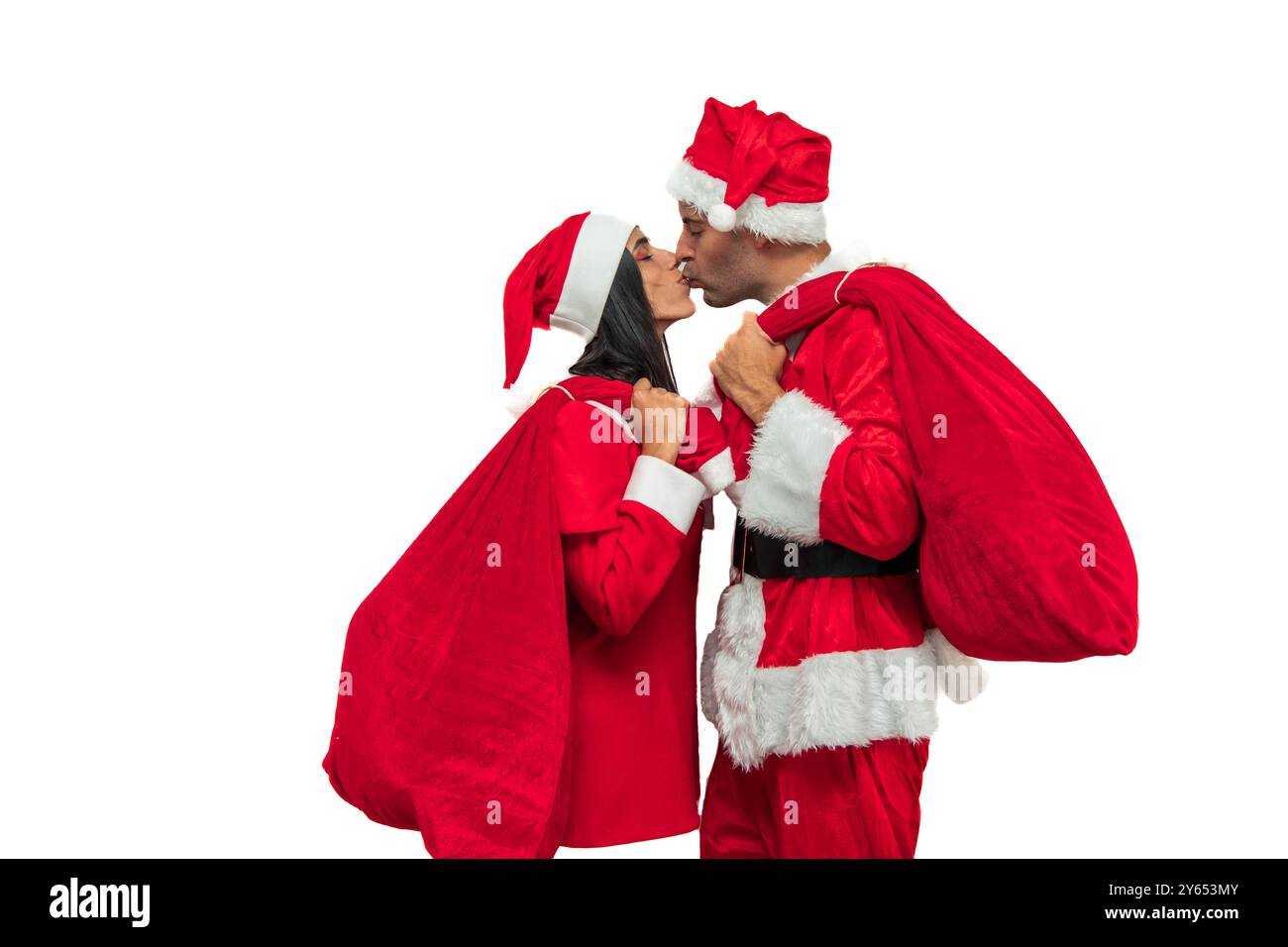 loving couple dressed in Santa Claus outfits shares a sweet kiss ...