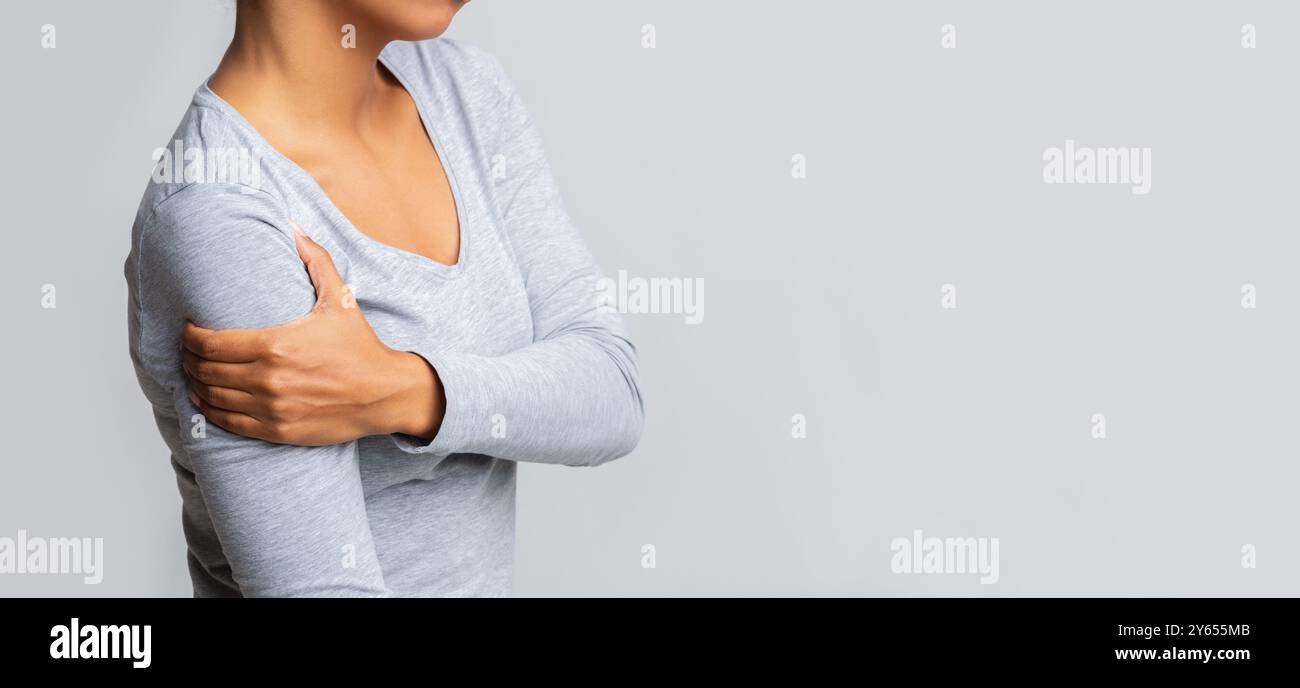 Afro woman holding her forearm over grey background Stock Photo - Alamy