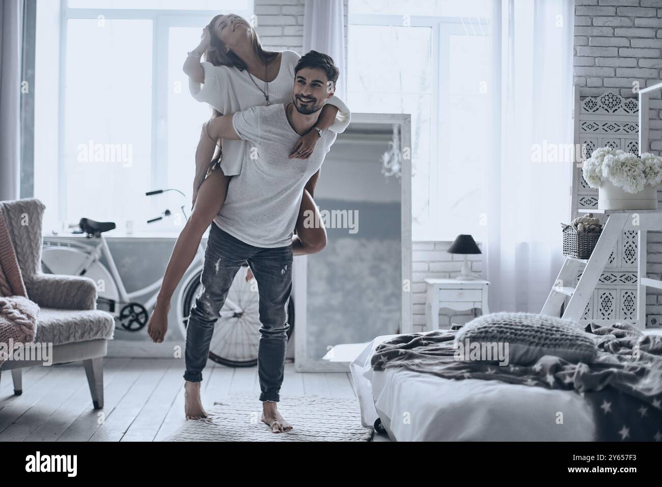 Always happy together. Young couple having fun in bedroom at home while handsome man giving his ...