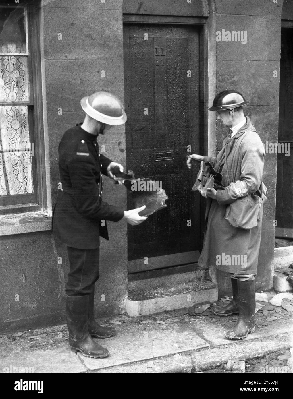 A fireman and an ARP warden examining bomb fragments after an air ...