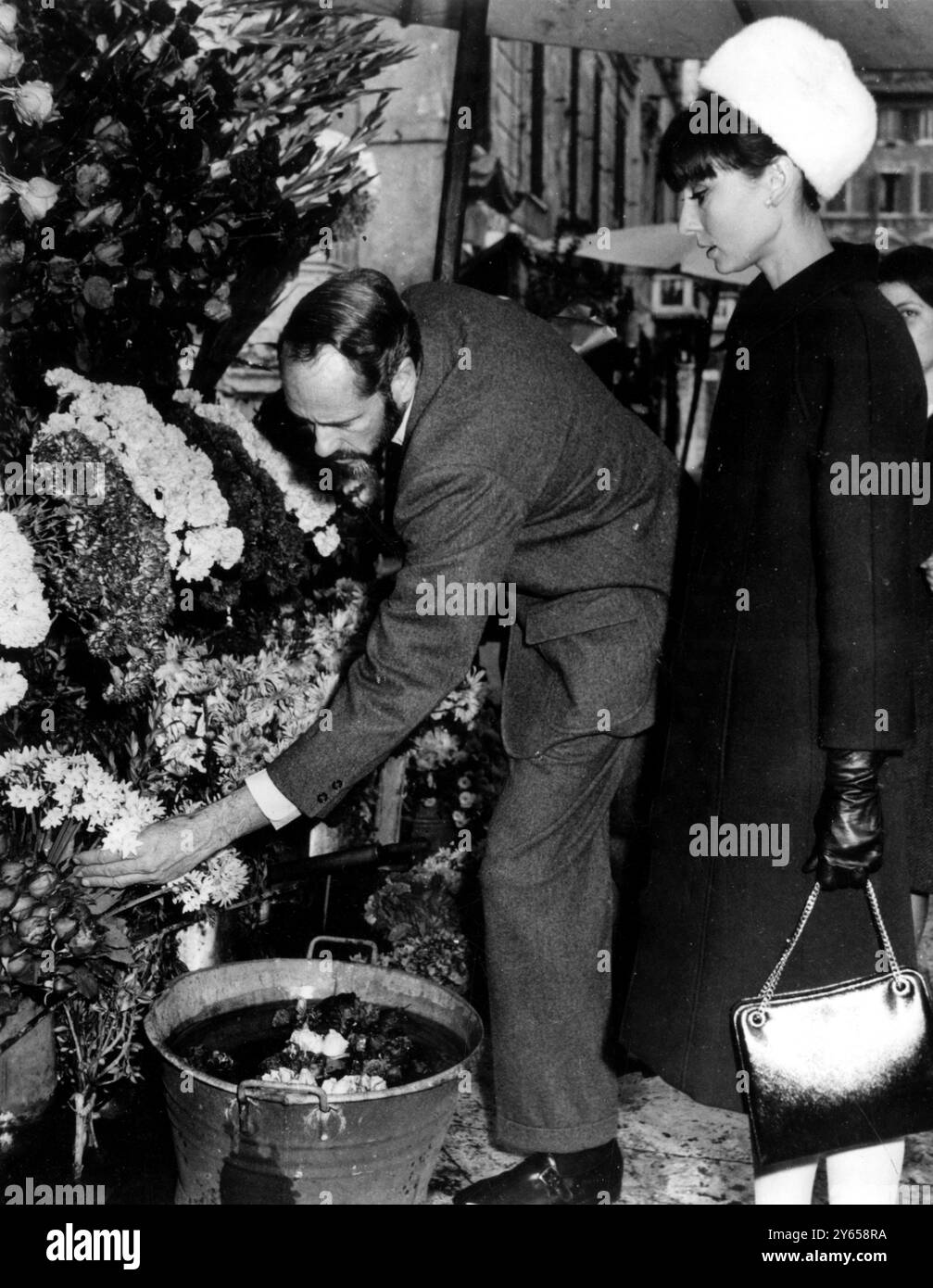 Actor Mel Ferrer picks up a bunch of jonquils for his wife Audrey ...